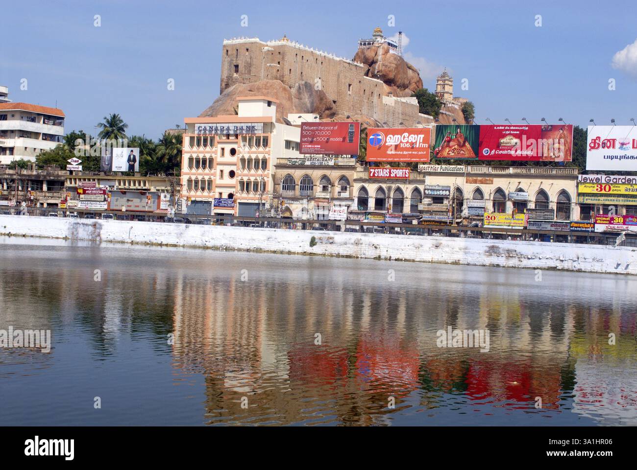 Rock fort with holy tank and pavilion surrounded by buildings and shops ...