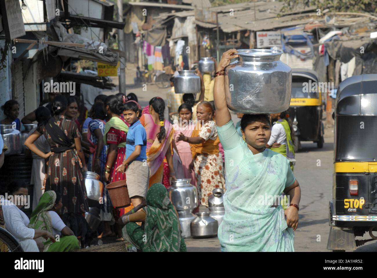 Women carry drinking water in aluminum containers on their heads at a ...