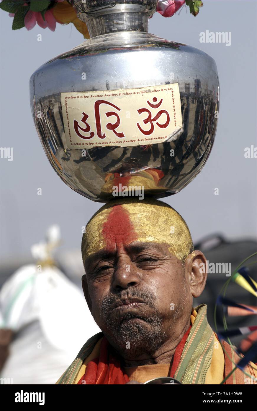 A saint, sadhu balance a stainless steel jar with flowers on his head ...