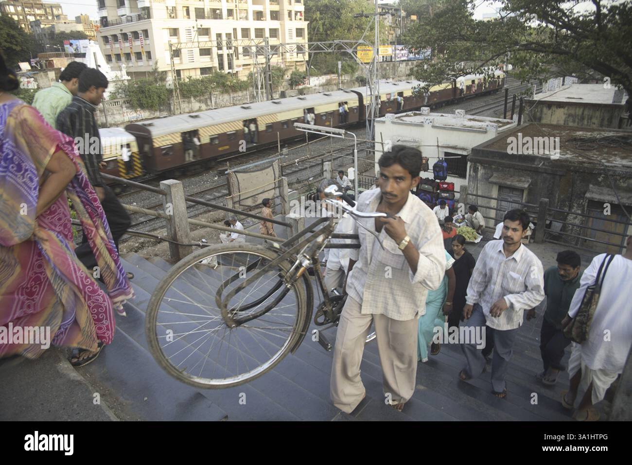 Bridge crowded near railway track man carrying cycle over staircase ...