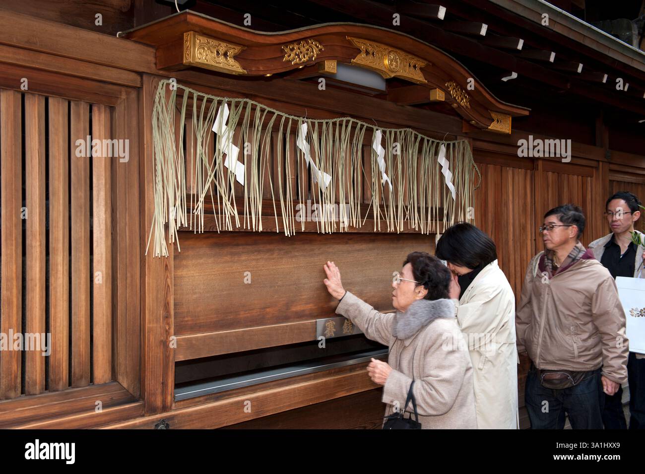 Worshipers touch, tap and pray at a wooden panel at Ebisu Jinja shrine ...