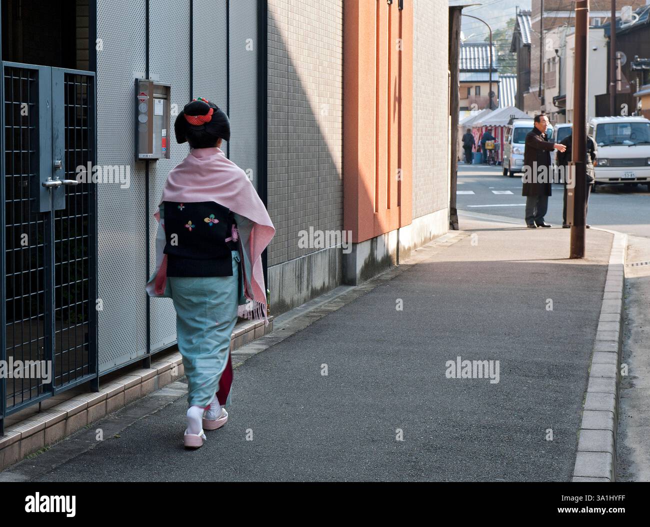 A Japanese maiko, or apprentice geisha or geiko, walking along a ...