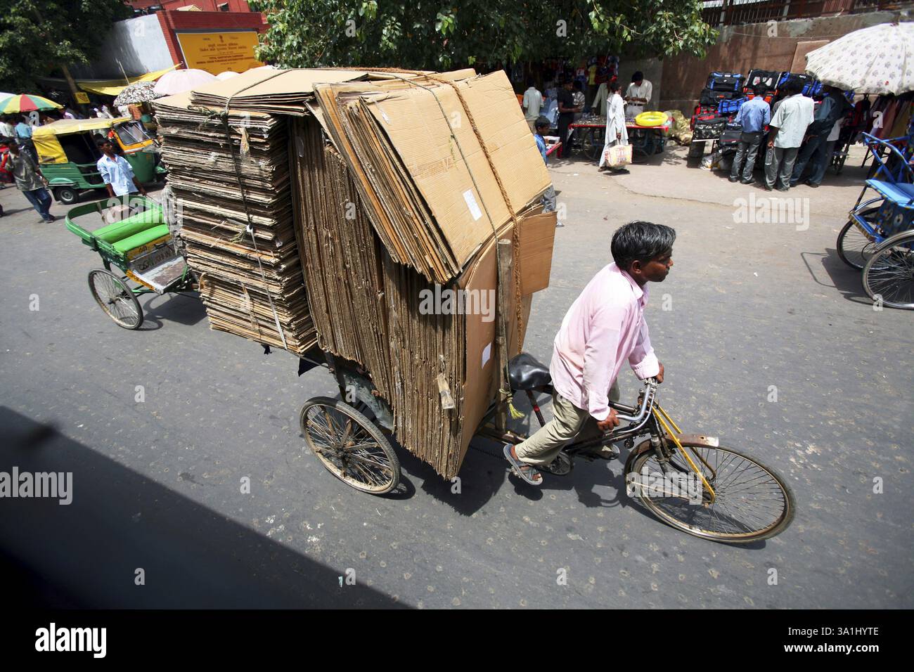 A tricycle rickshaw loaded with dismantled card board boxes being ...