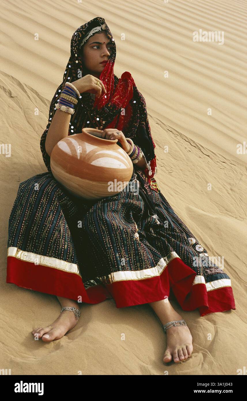 Rajasthani Woman holding clay pot sitting on sand and waiting, Bikaner ...