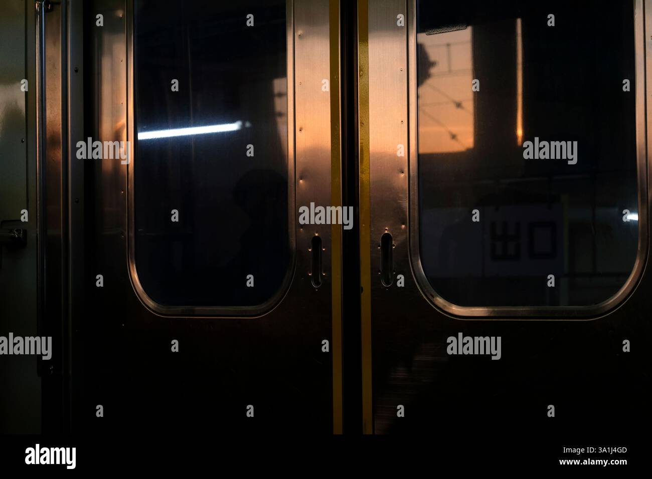 The evening sky reflected on the metal doors of a Japanese metro train ...
