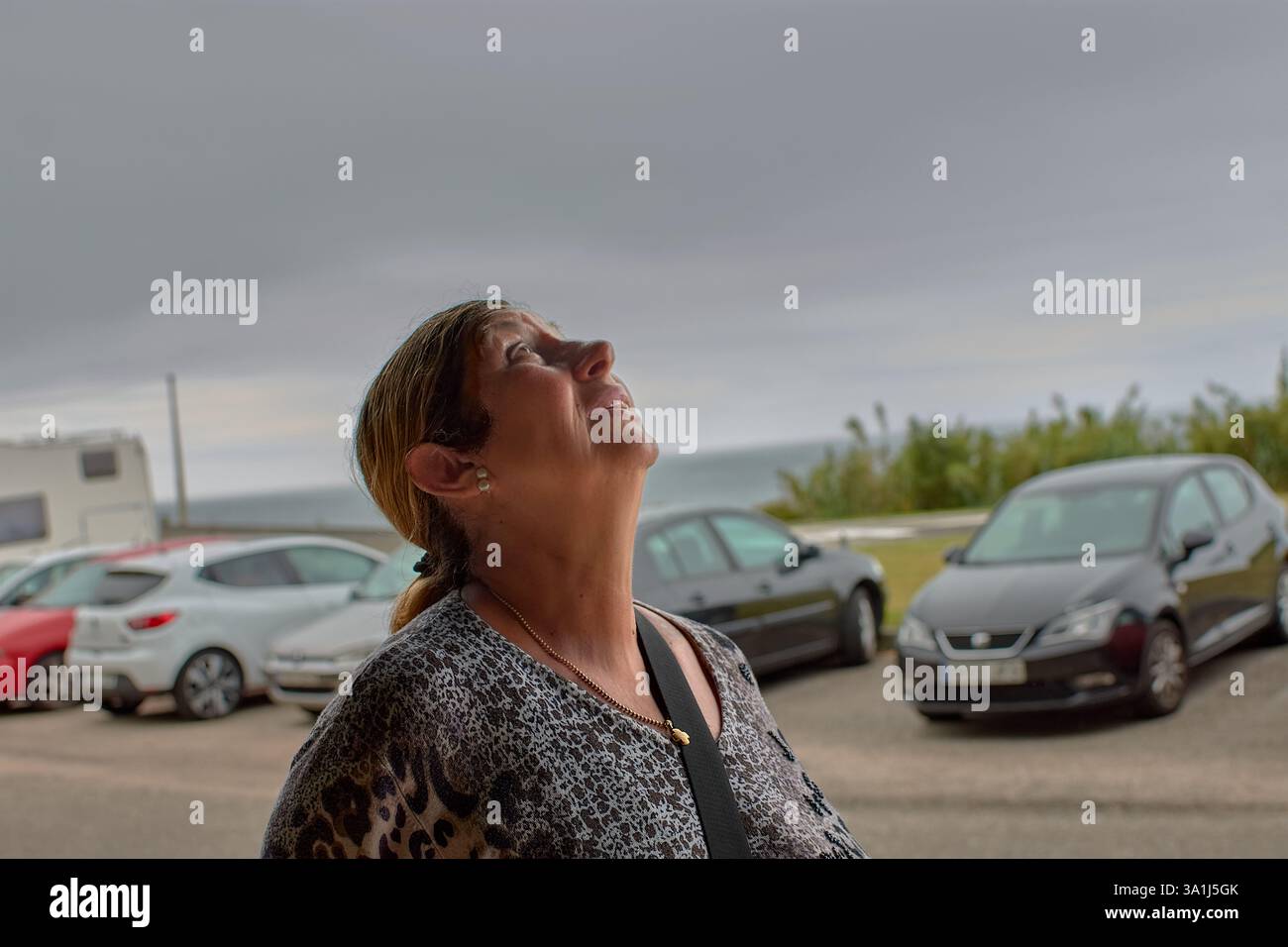 A retired woman looks up at the sky, checking for signs of rain while ...