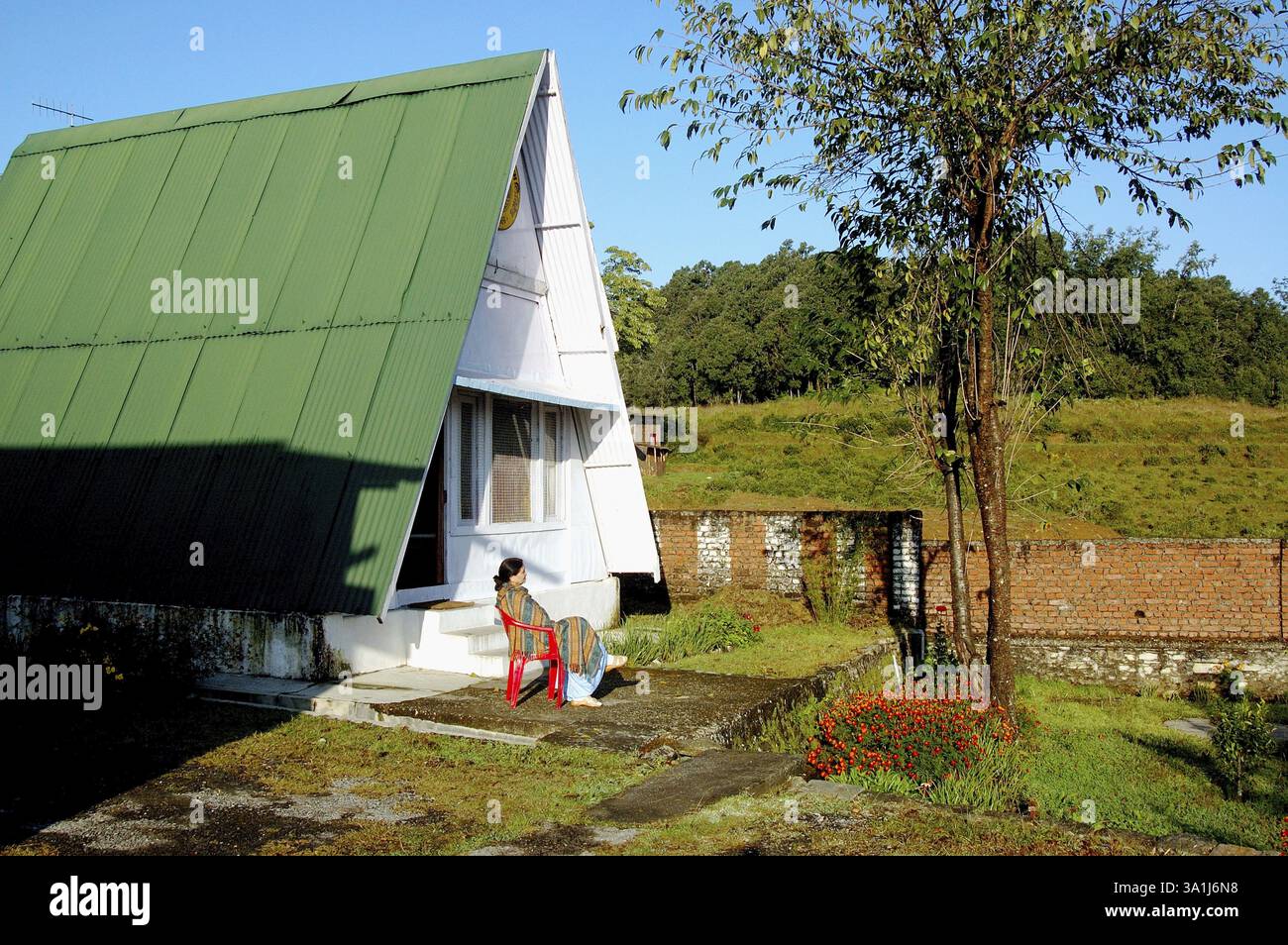 Old lady sitting on chair outside hut at tourist resort at Chakori ...