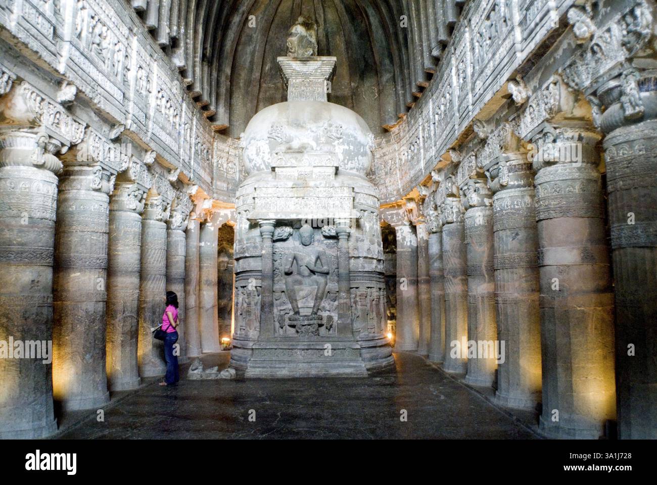 Statue of god Buddha and tourists watching pillars in Ajanta caves ...