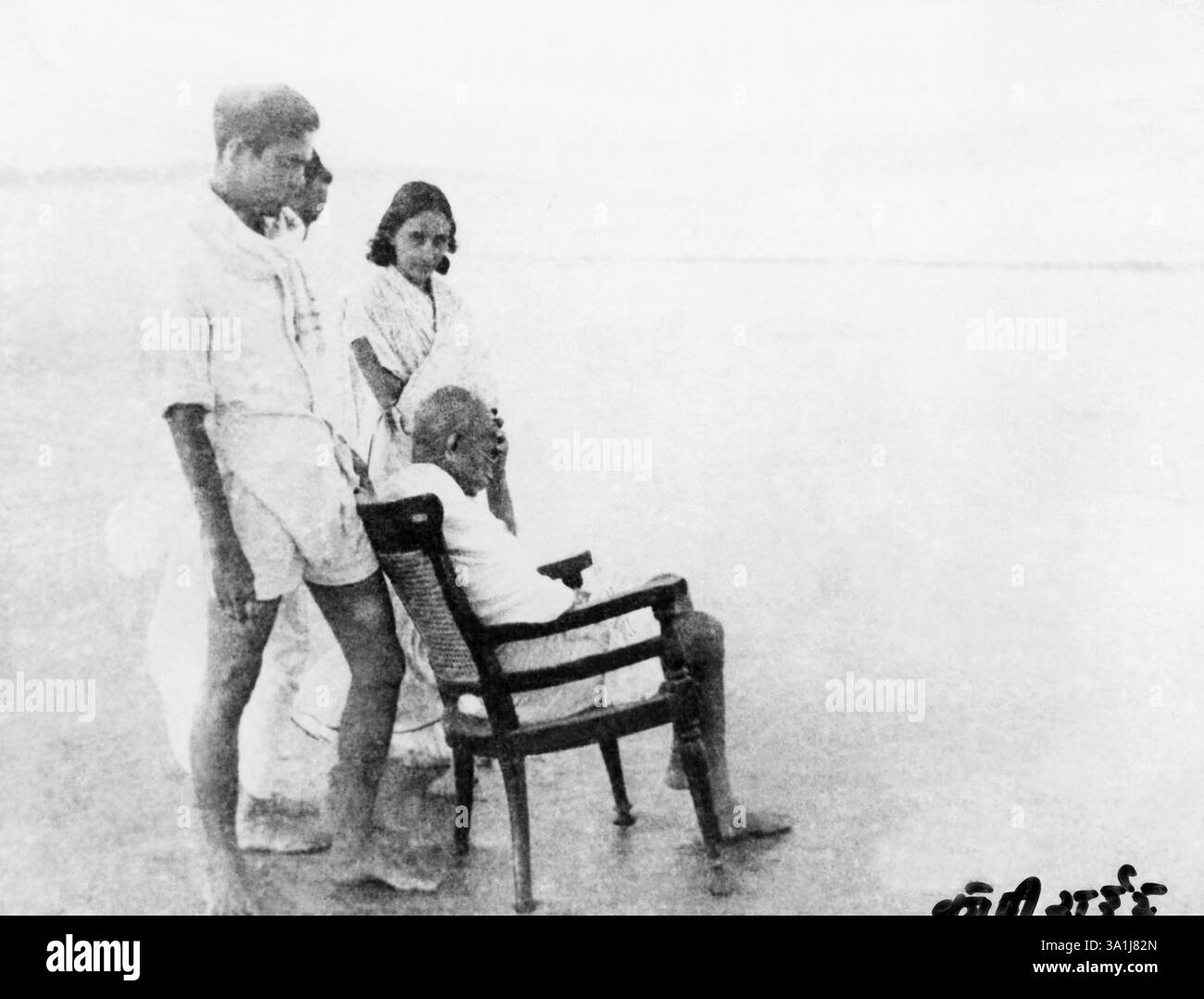 Mahatma Gandhi, sitting in a chair Juhu Beach, Mumbai, with people ...