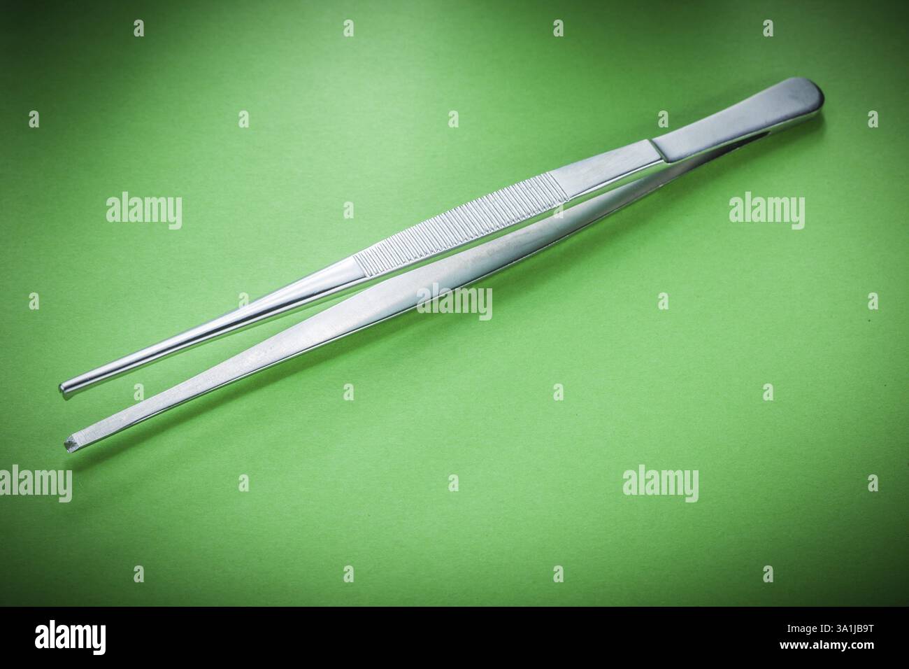 Medical forceps on green background medicine concept Stock Photo - Alamy