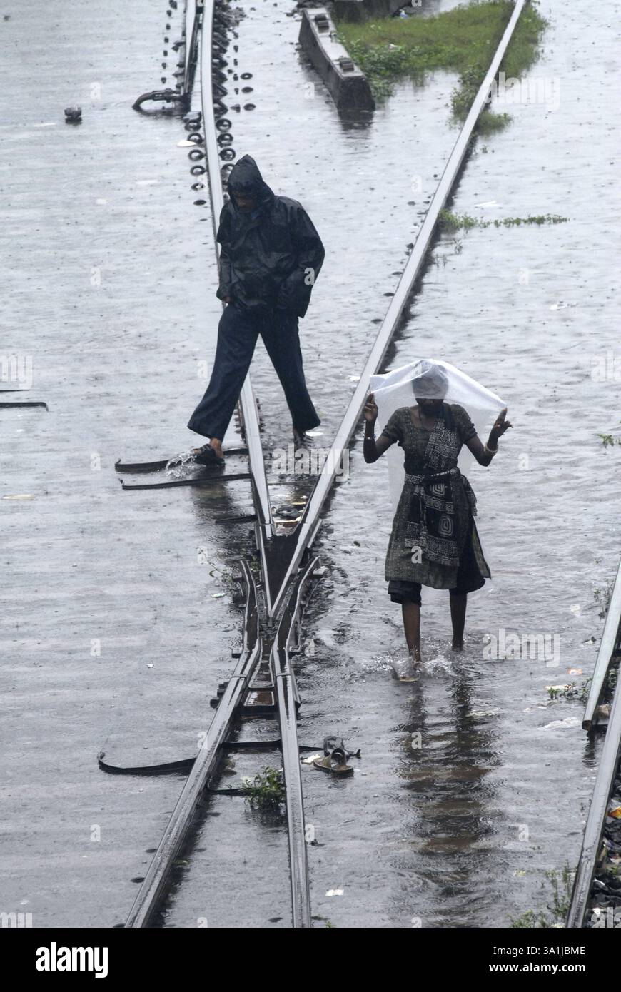 Commuters walk in the flooded waters on the railway tracks caused due to heavy rains at Kurla ...