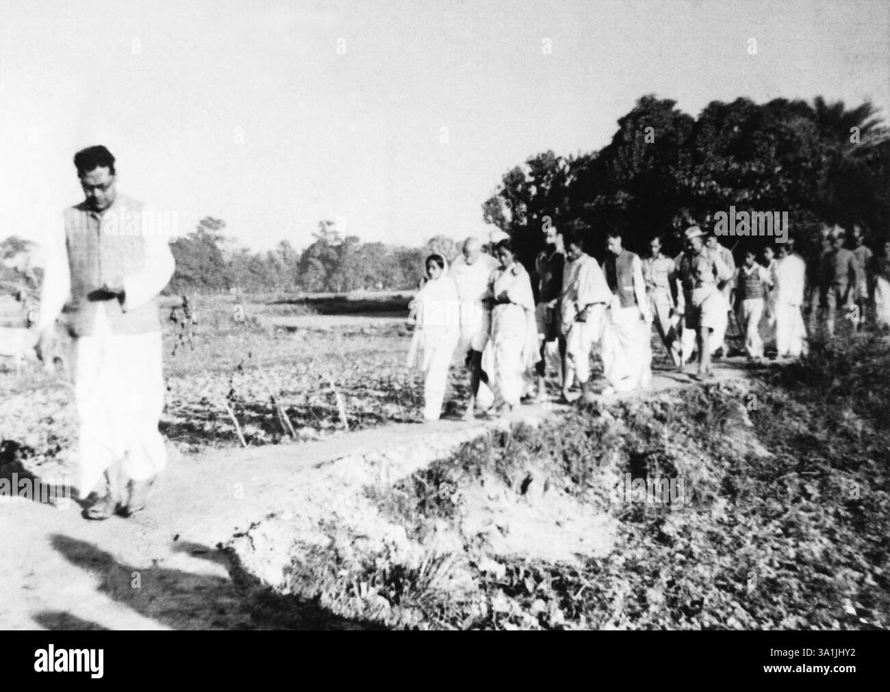 Mahatma Gandhi, supported by Amtus Salam and Abha Gandhi, walking with ...