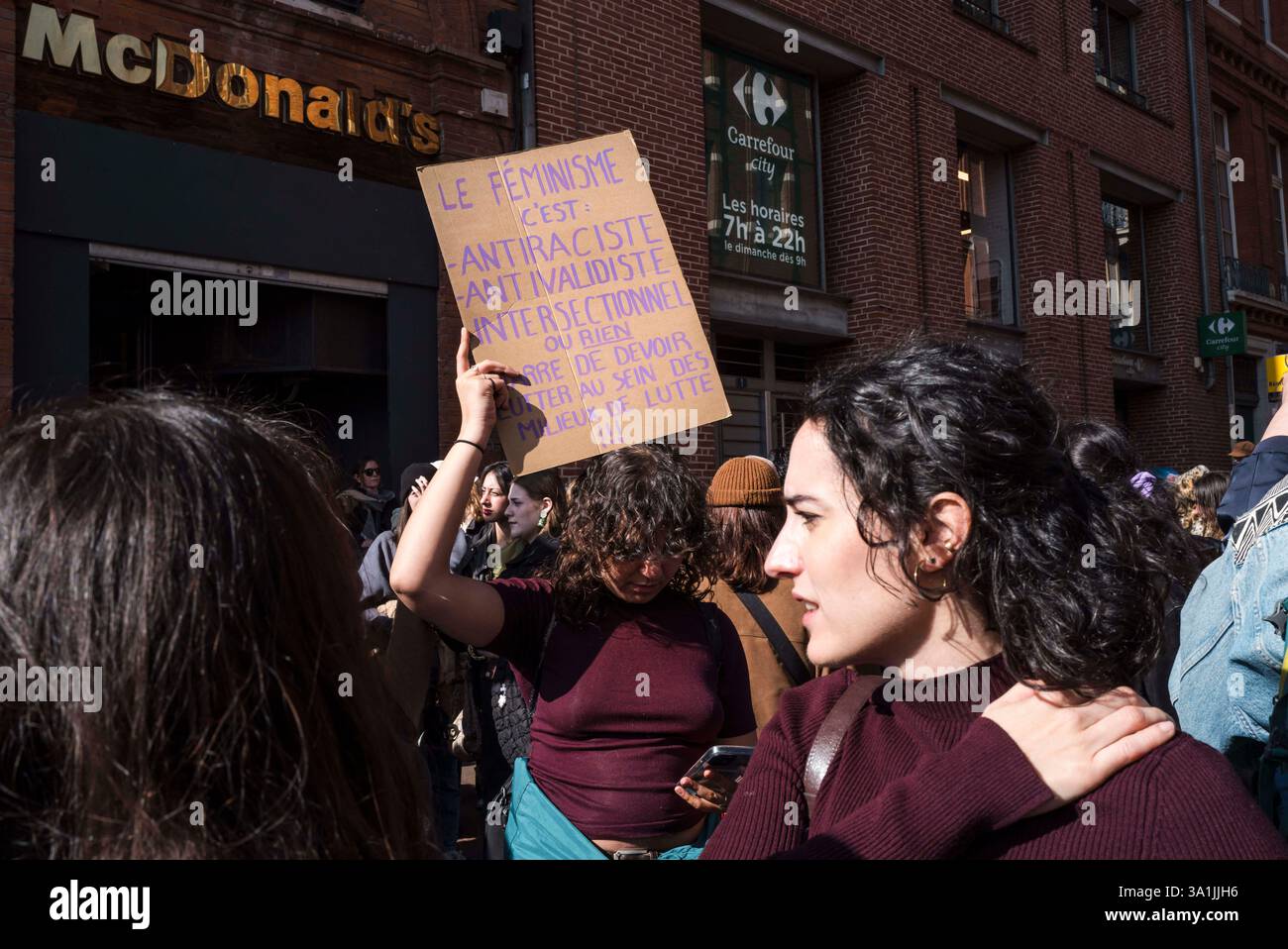 A demonstrator with a placard, Feminism is anti-racist, anti ...
