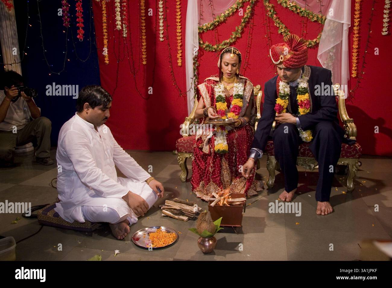 Pundit chanting mantra and bride and bridegroom offering in holy fire ...
