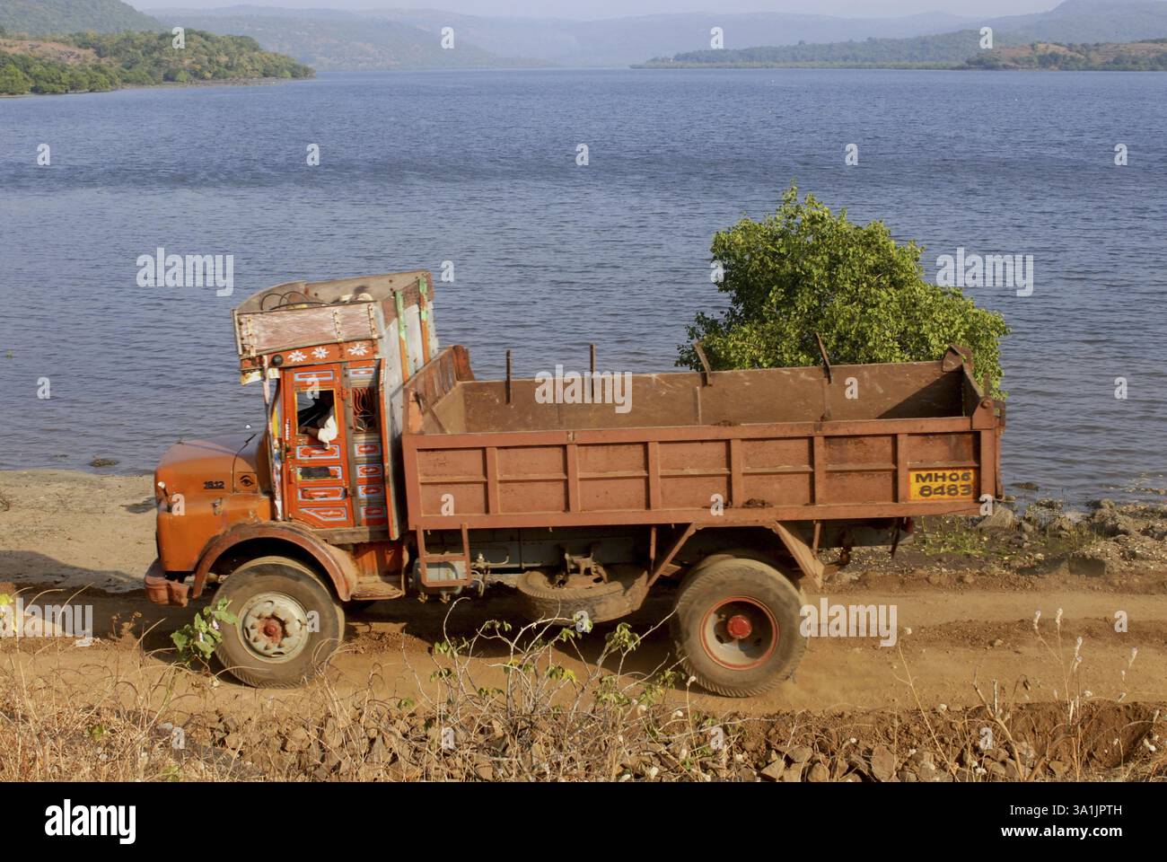 Truck at work, mangroves and marshy land of Bankot creek at Bagmandala ...