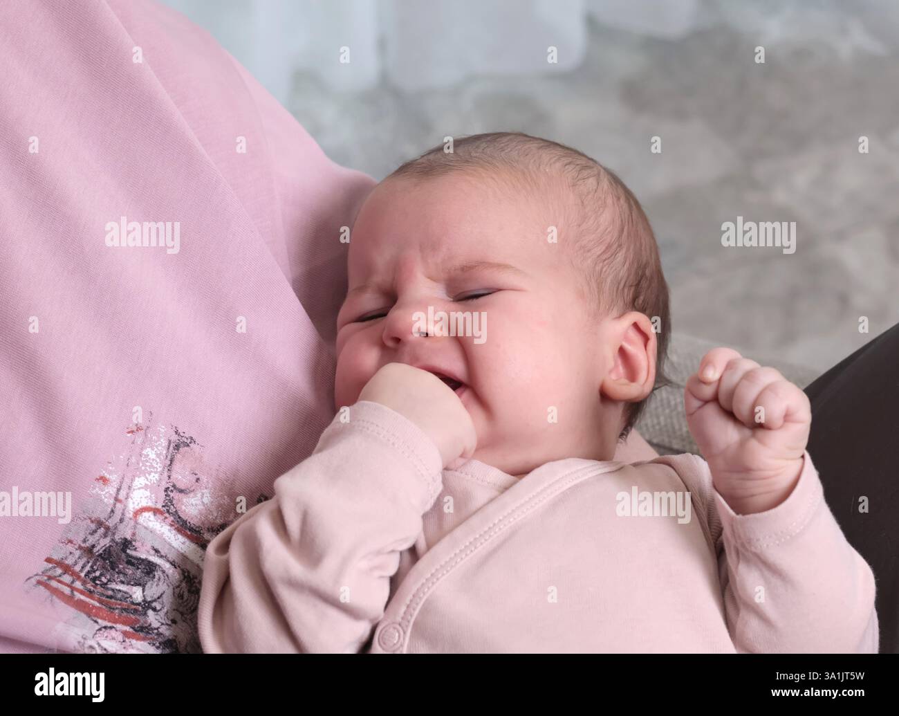 Newborn baby girl in pink clothes is cranky, crying and uncomfortable ...
