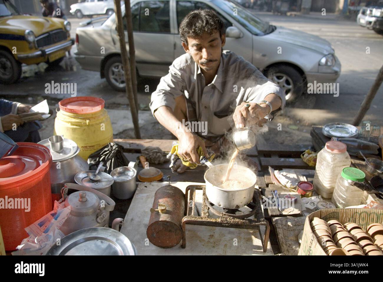 Tea vendor pouring steam tea from cup into teapot, Calcutta NAw Kolkata ...
