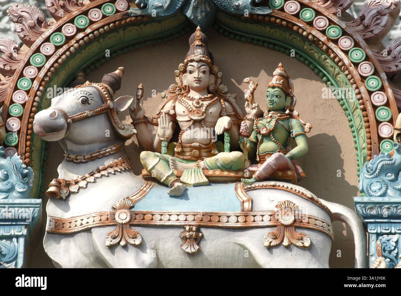 Colourfully painted sculptures of lord Shiva with Parvati sitting on ...
