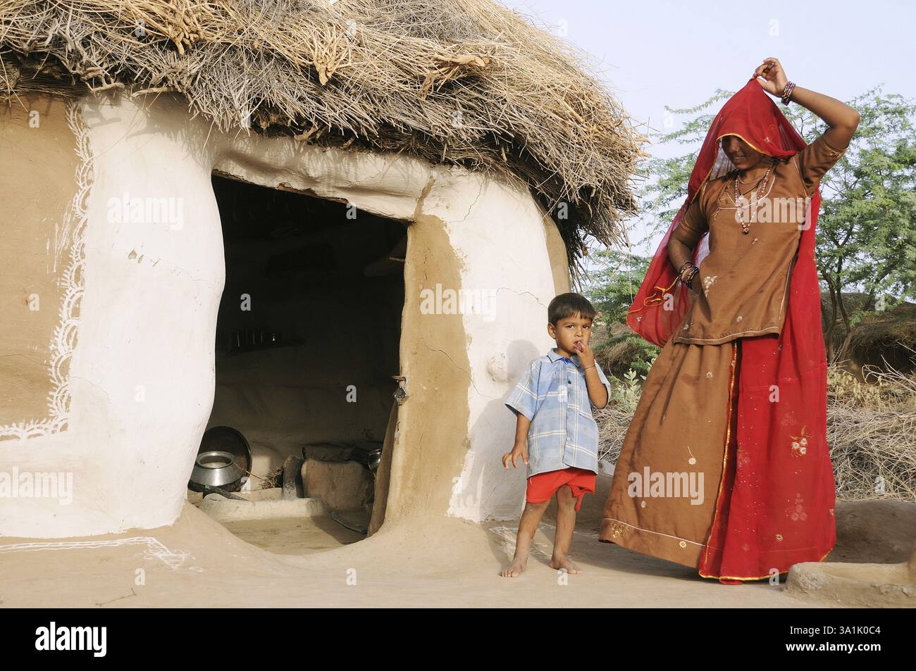 Lady standing outside hut with her child, Sujangarh, Rajasthan, India ...