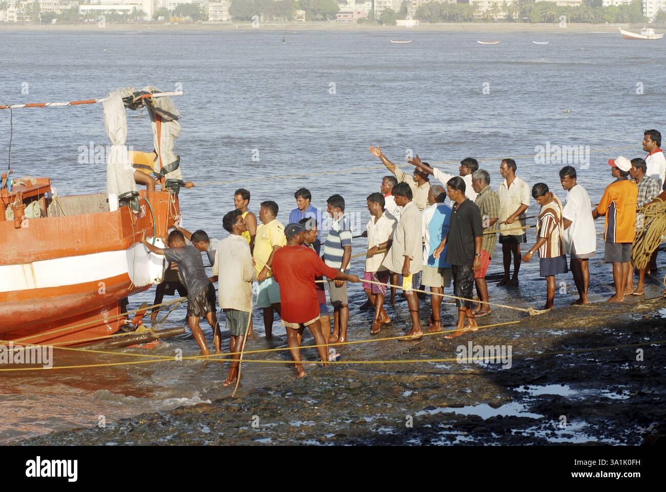 Fishermen preparing to pull boat on shore for repairs and maintenance ...