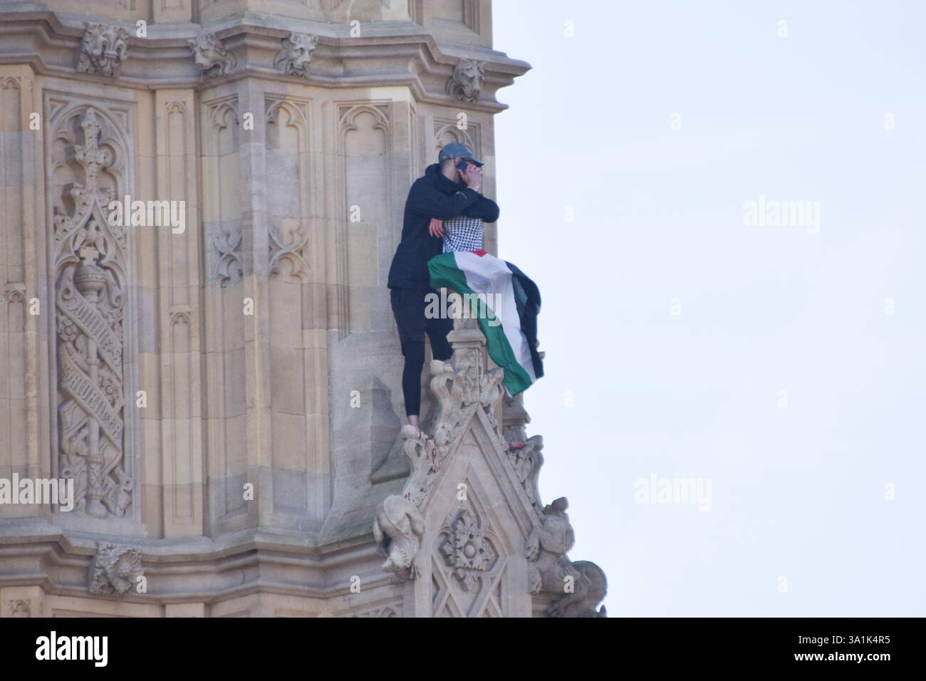 London, UK. 8th March 2025. A man with a Palestine flag scales ...