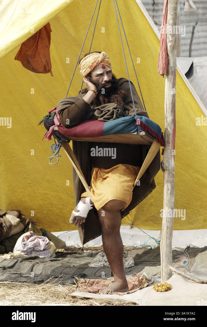 A sadhu from the Juna Akadha sits with his Trishul at their camp during ...