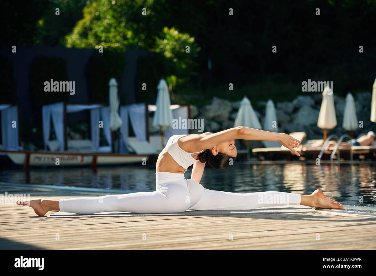 Flexible body. Woman near pool is doing yoga exercises Stock Photo - Alamy