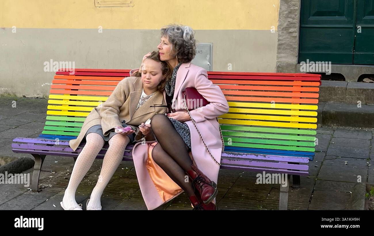 Grandmother hugs her granddaughter while sitting on a bench of LGBT ...