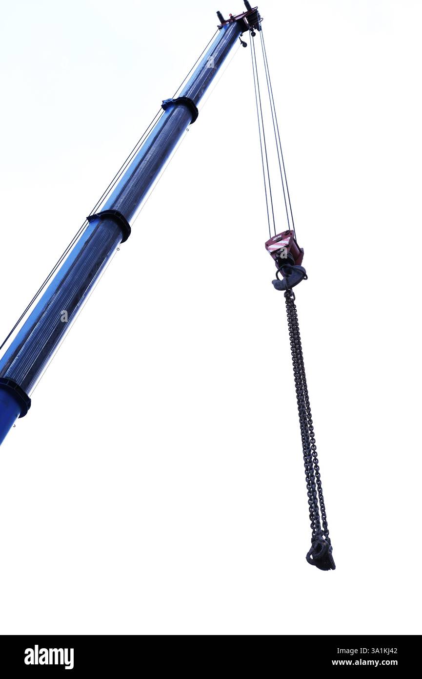 Blue crane arm vertical, boom with hanging hook against clear sky ...