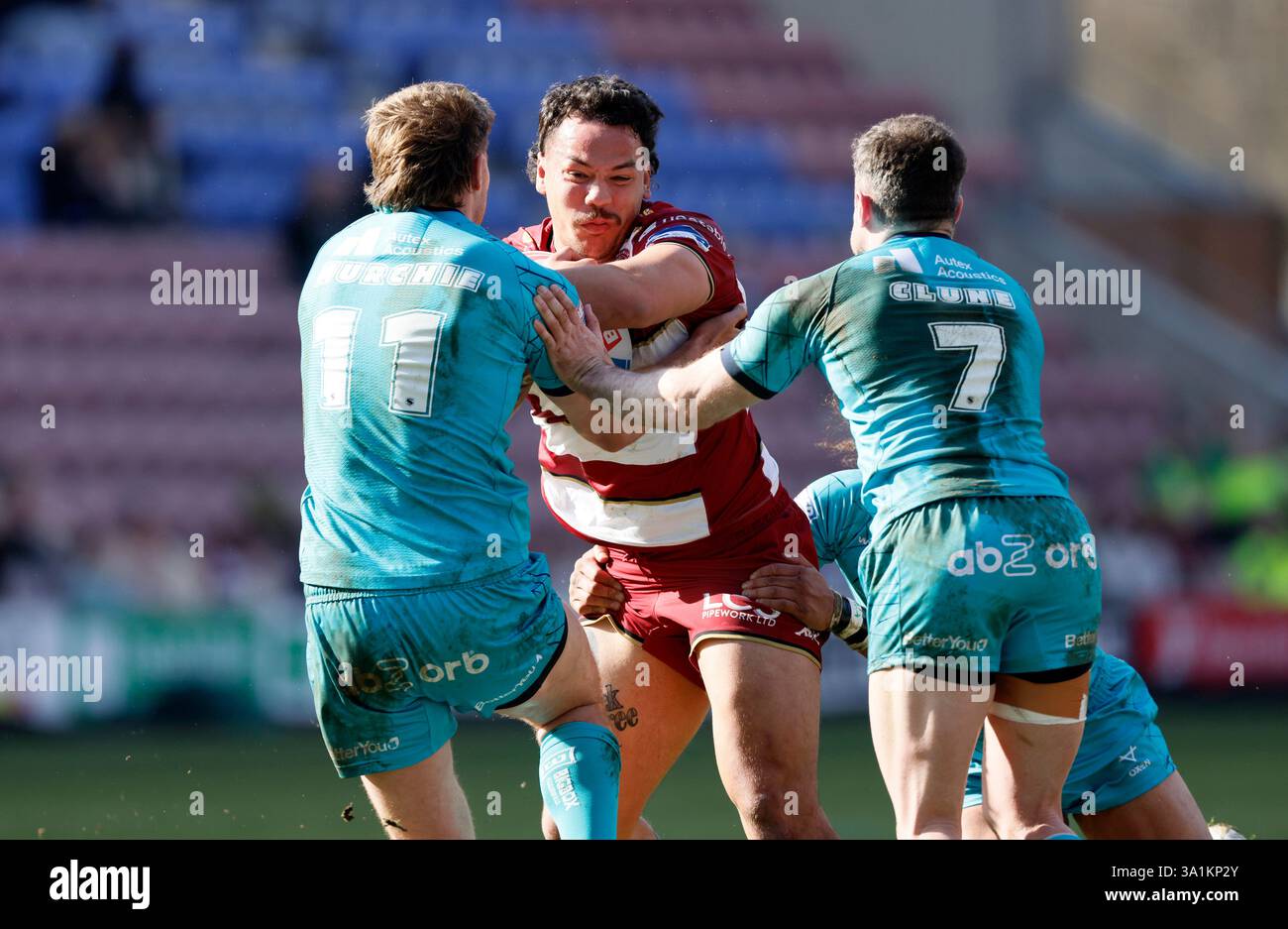Wigan's Tyler Dupree is tackled Huddersfield's Jack Murchie by during ...