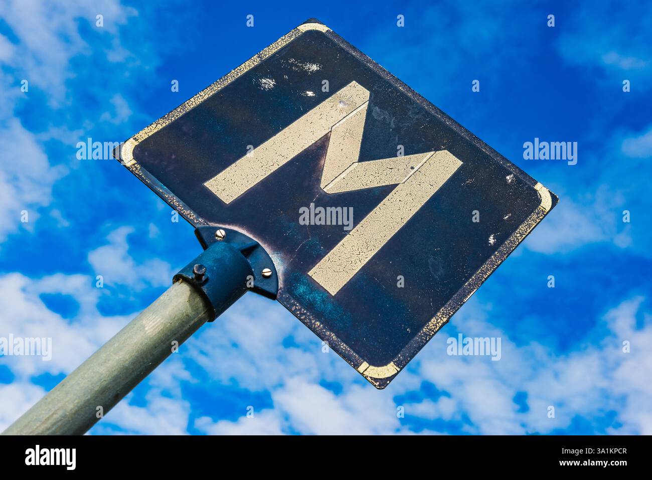 A road sign displaying the letter M stands prominently against a ...