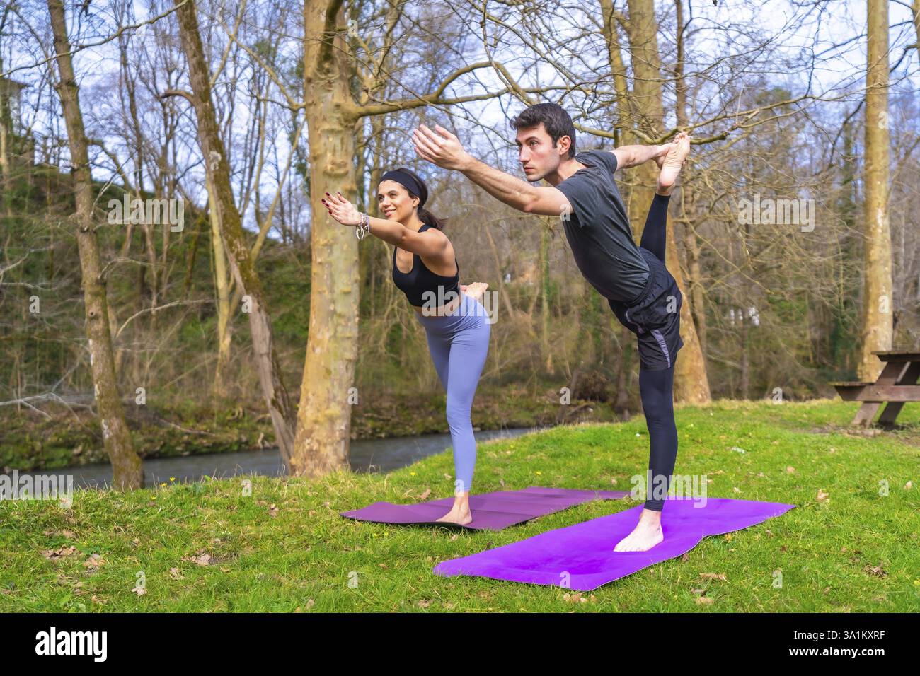 Couple practicing yoga outdoors, demonstrating balance and flexibility ...