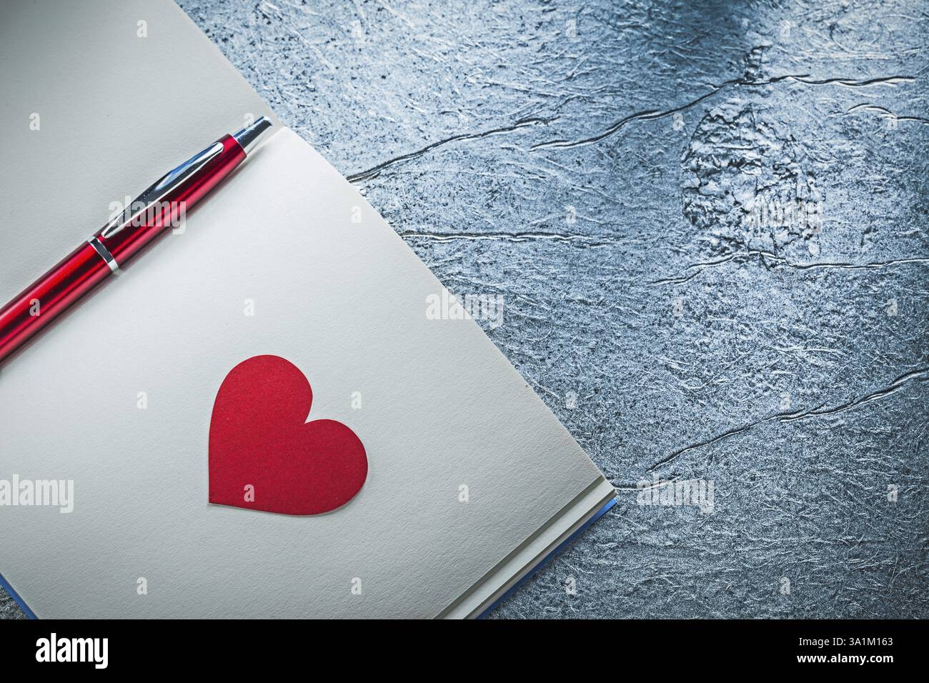 Red heart biro pen NAtepad on metallic background education concept ...
