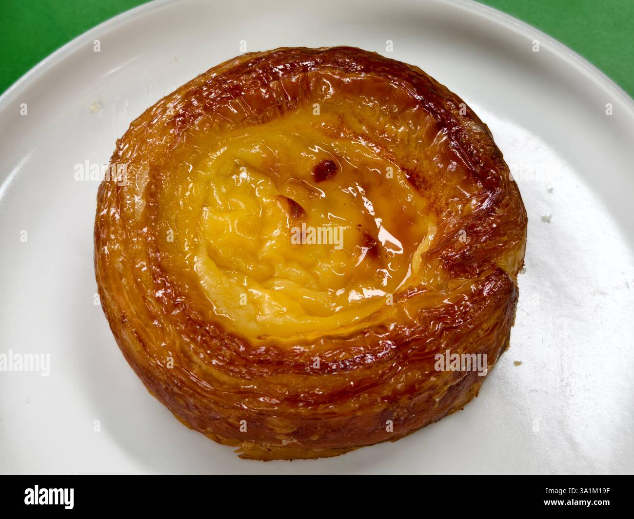 A golden custard Danish pastry with a caramelized top and a flaky ...