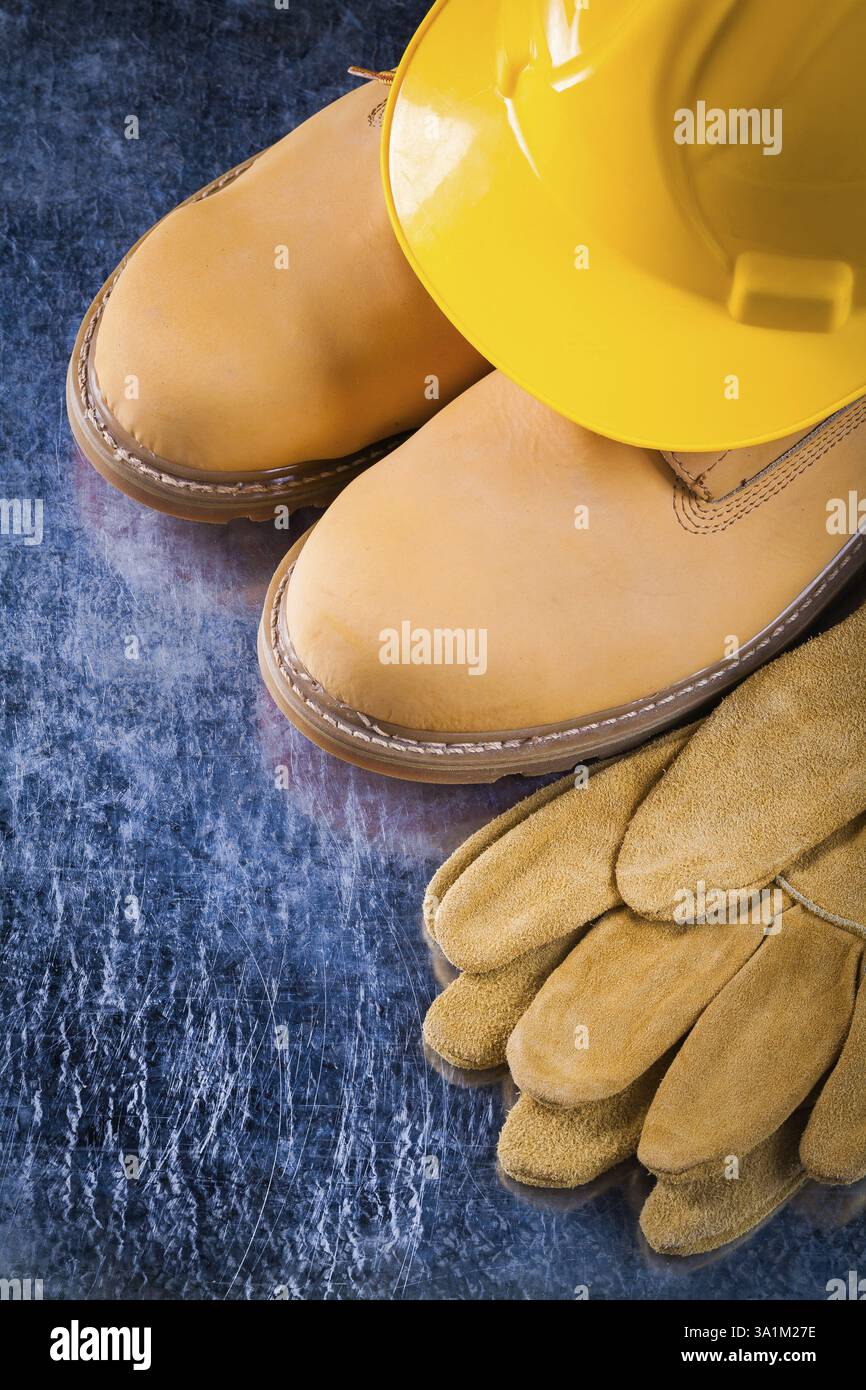 Pair of safety boots gloves and working helmet on scratched metallic ...