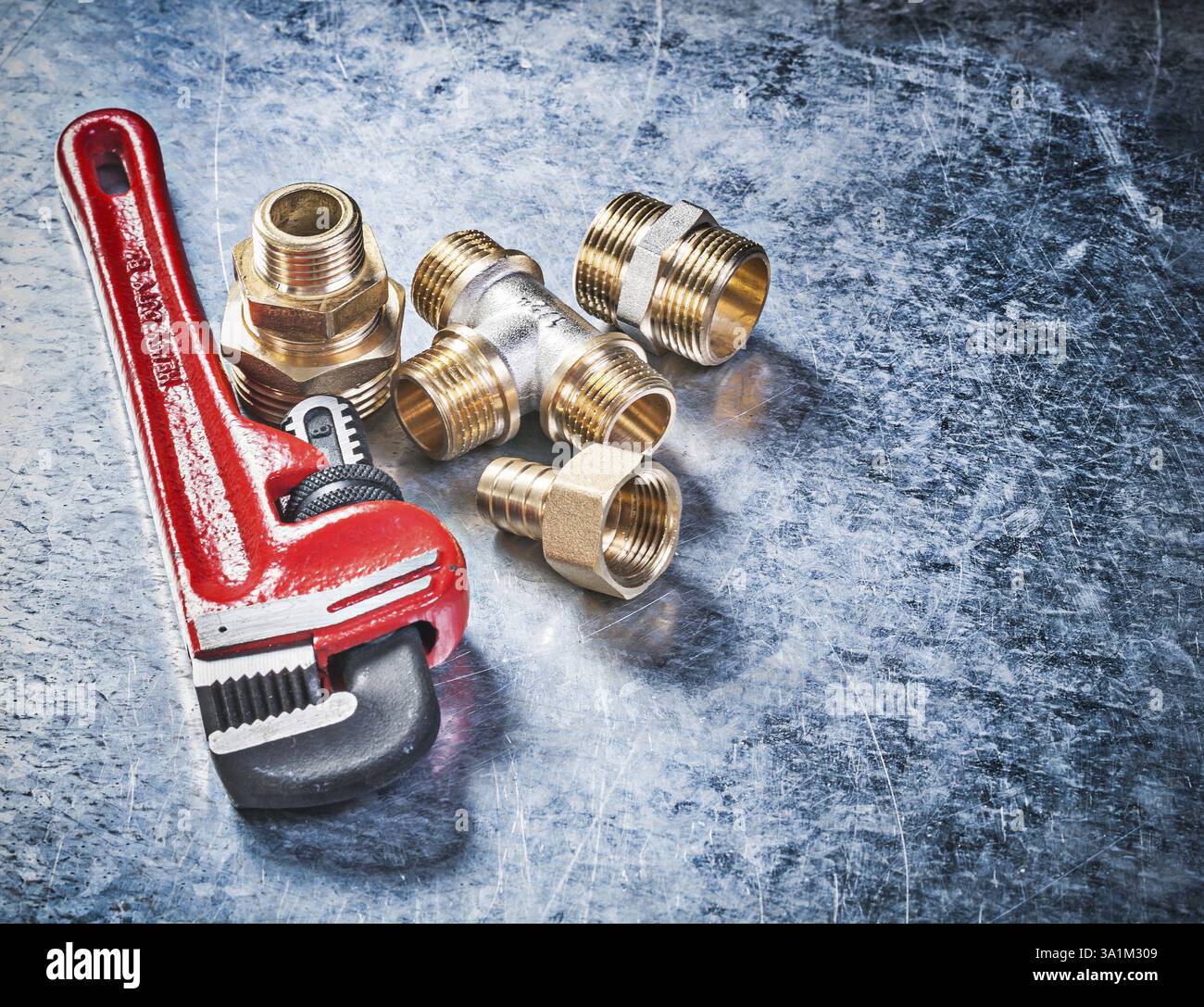 Pipe wrench brass hose nipples on scratched metallic background ...