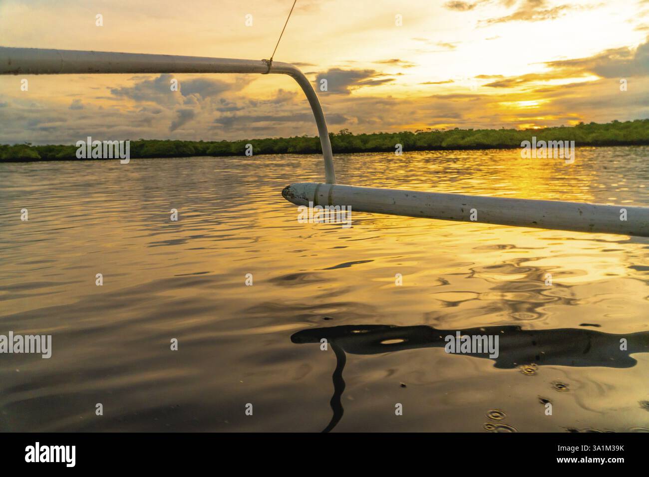 Outrigger of a banca boat sailing on calm water during a golden sunset ...