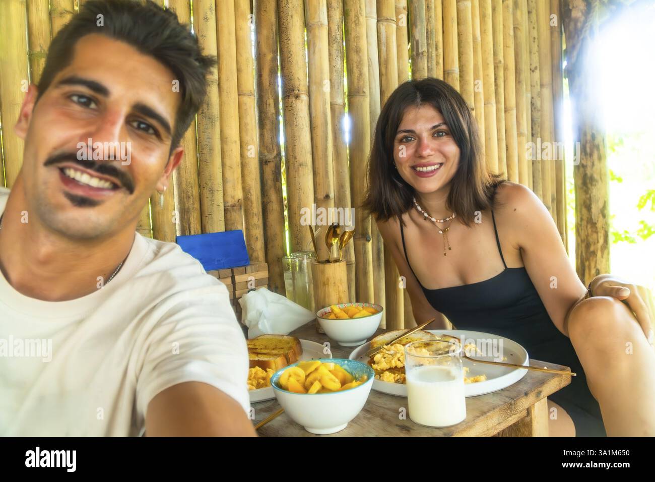 Tourists having breakfast with mango and scrambled eggs in a bamboo hut ...