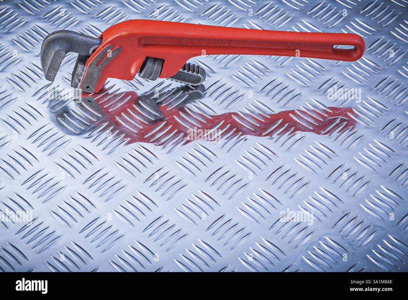 Metal pipe wrench on corrugated metallic background directly above ...