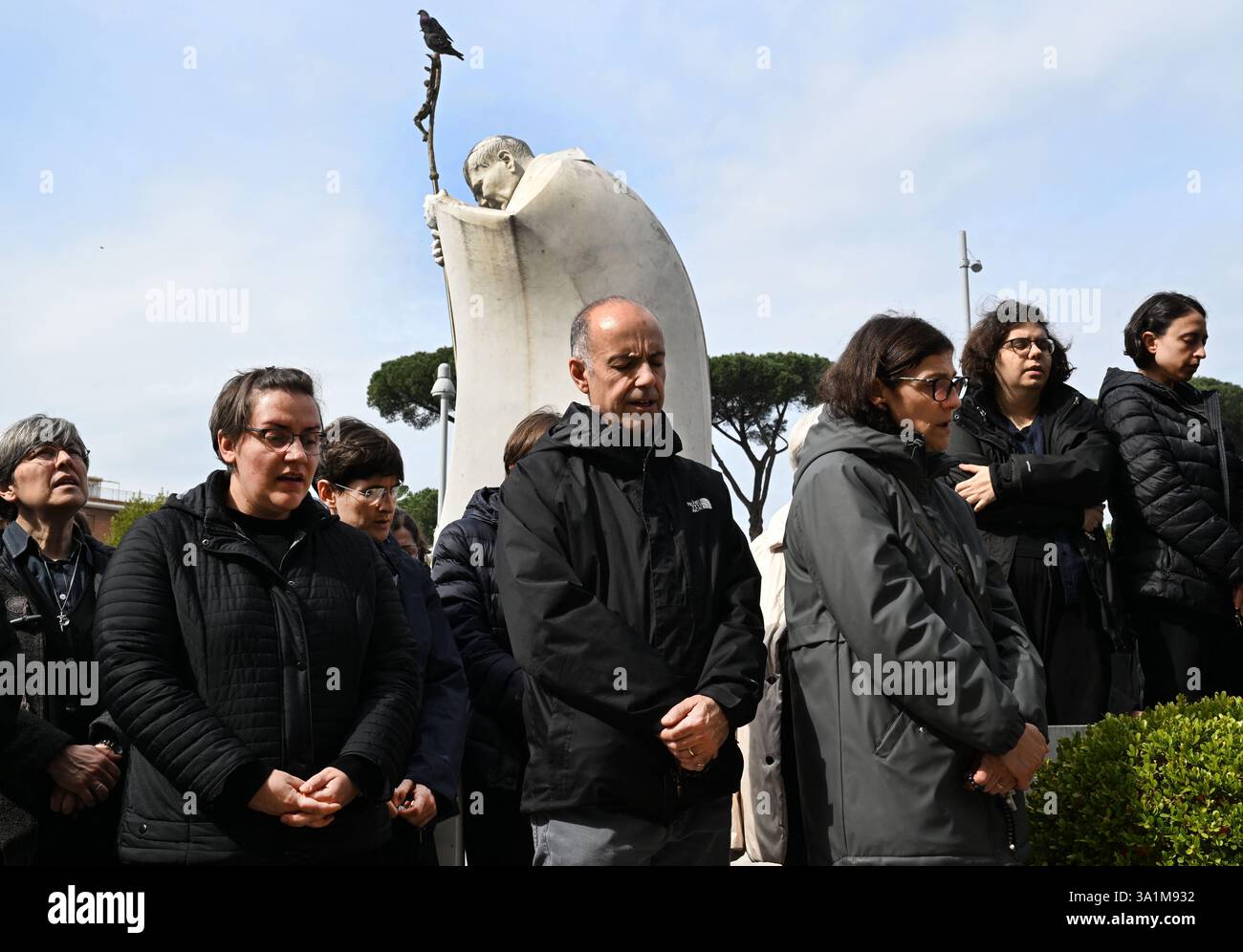 Rome, Italy. 09th Mar, 2025. People pray near the statue of John Paul ...
