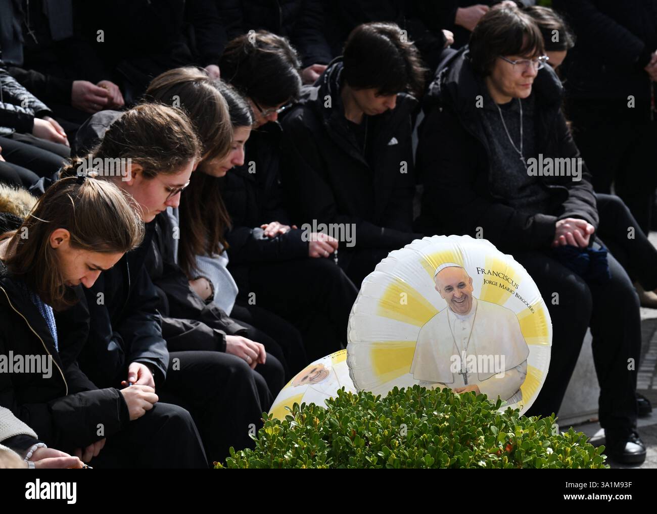 People pray near the statue of John Paul II outside the Gemelli ...