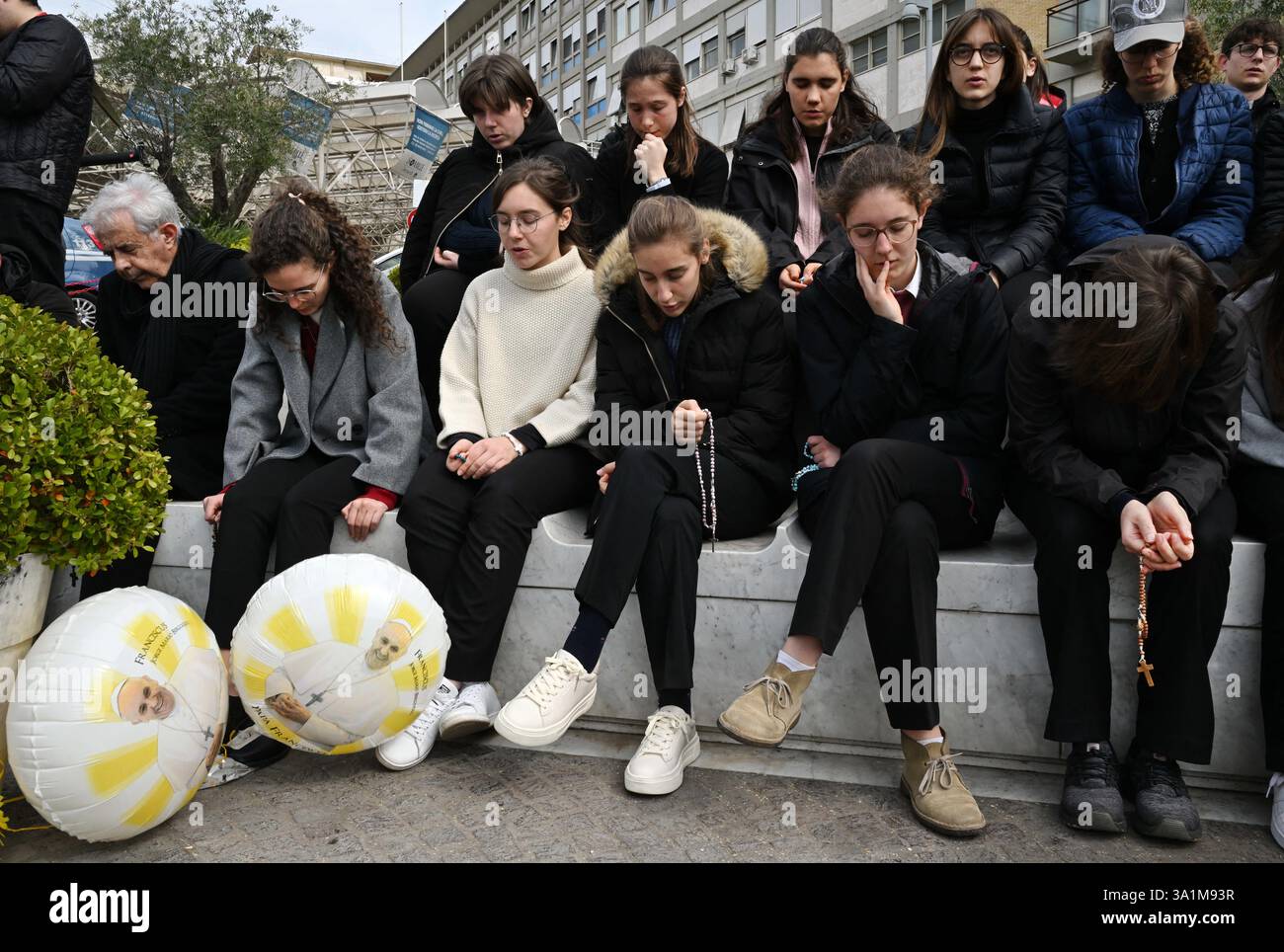 People pray near the statue of John Paul II outside the Gemelli ...
