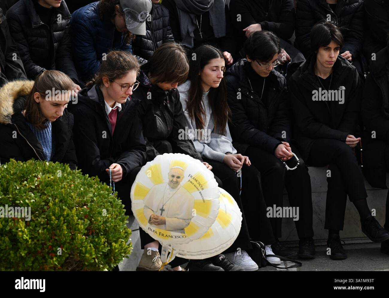 People pray near the statue of John Paul II outside the Gemelli ...
