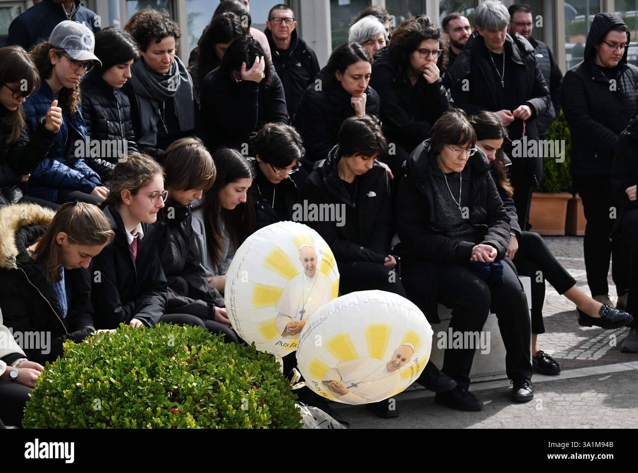 People pray near the statue of John Paul II outside the Gemelli ...