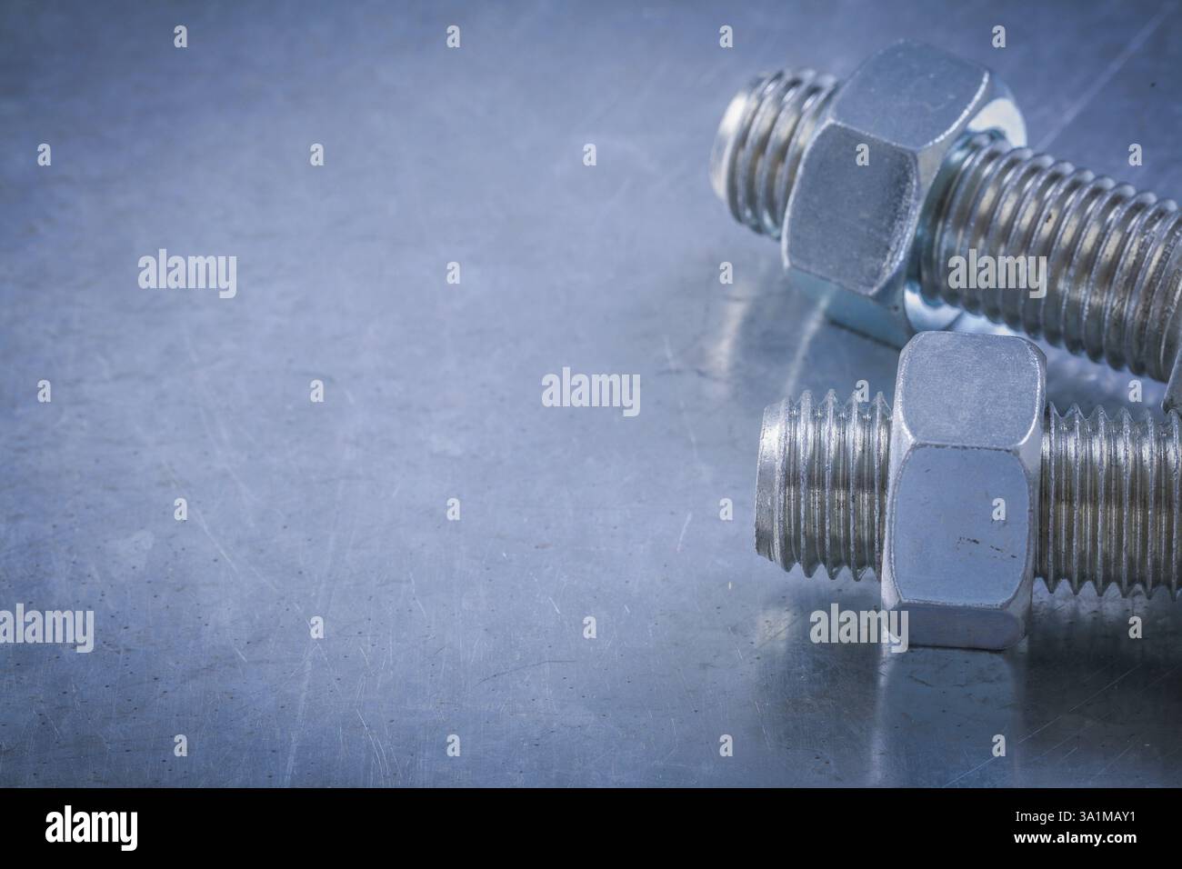 Pair of threaded bolts construction nuts on metallic background ...