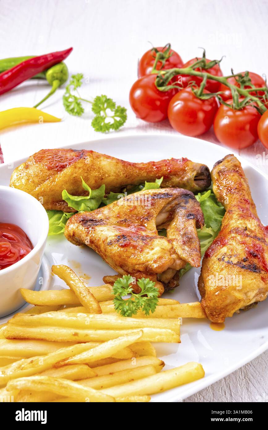 Grilled chicken wings, legs, chips and vegetables Stock Photo - Alamy