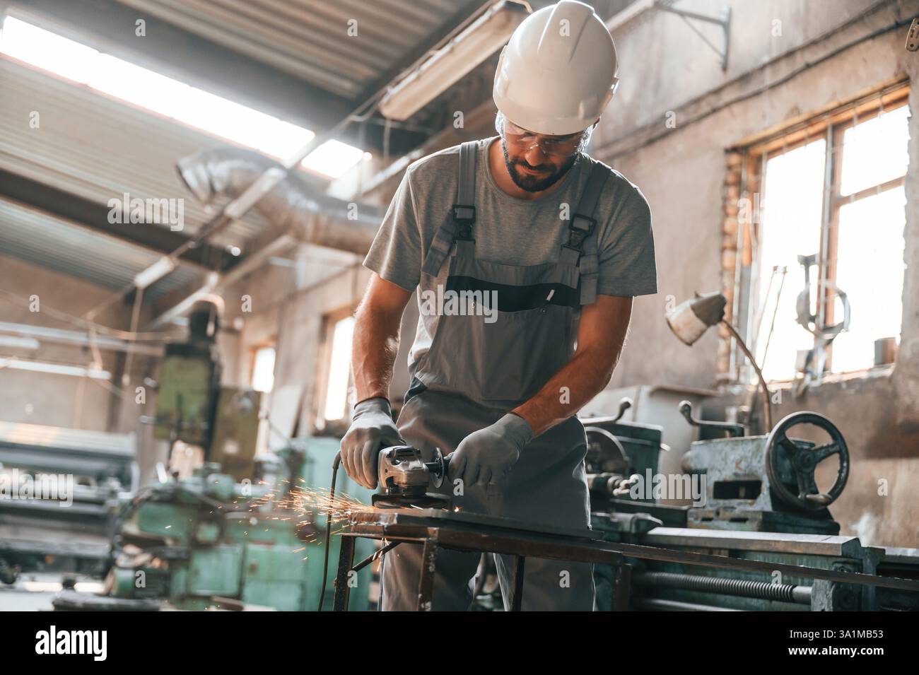 Busy day. Young factory worker in grey uniform Stock Photo - Alamy