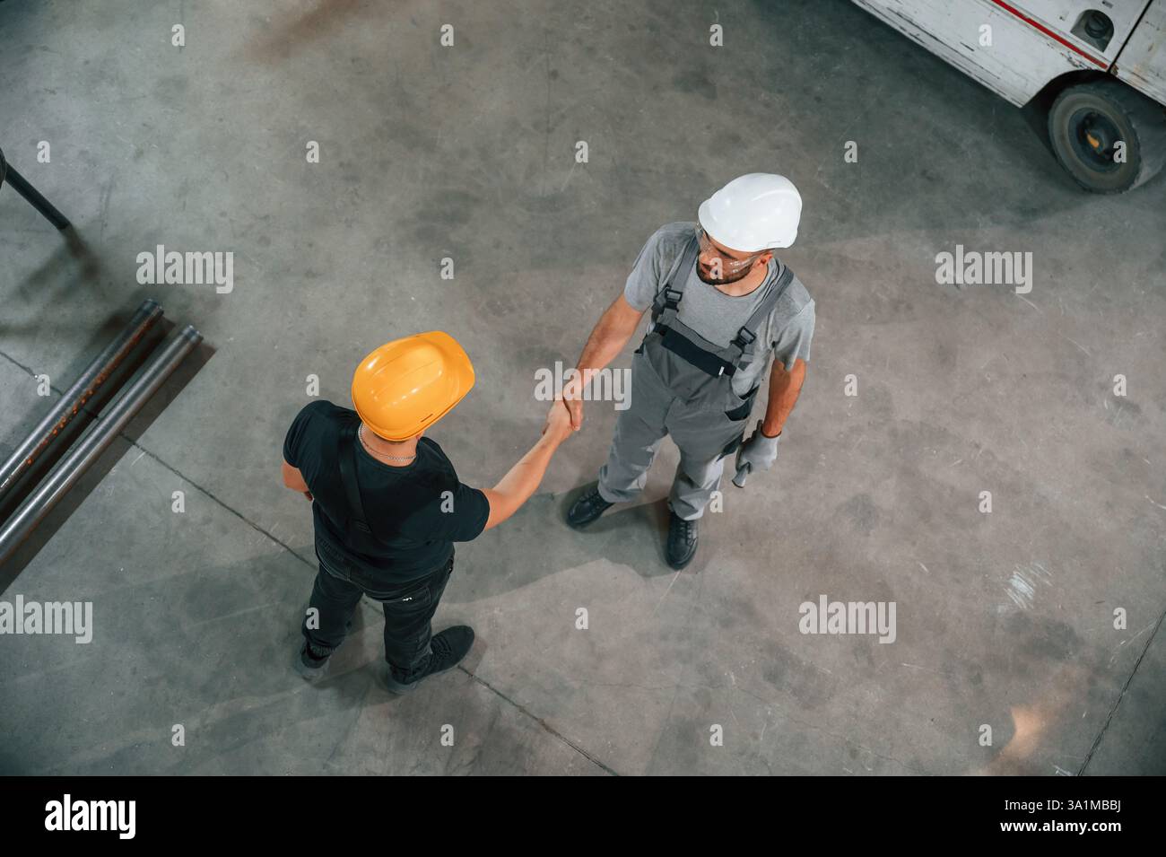 Top view of two factory workers that are standing and making handshake ...