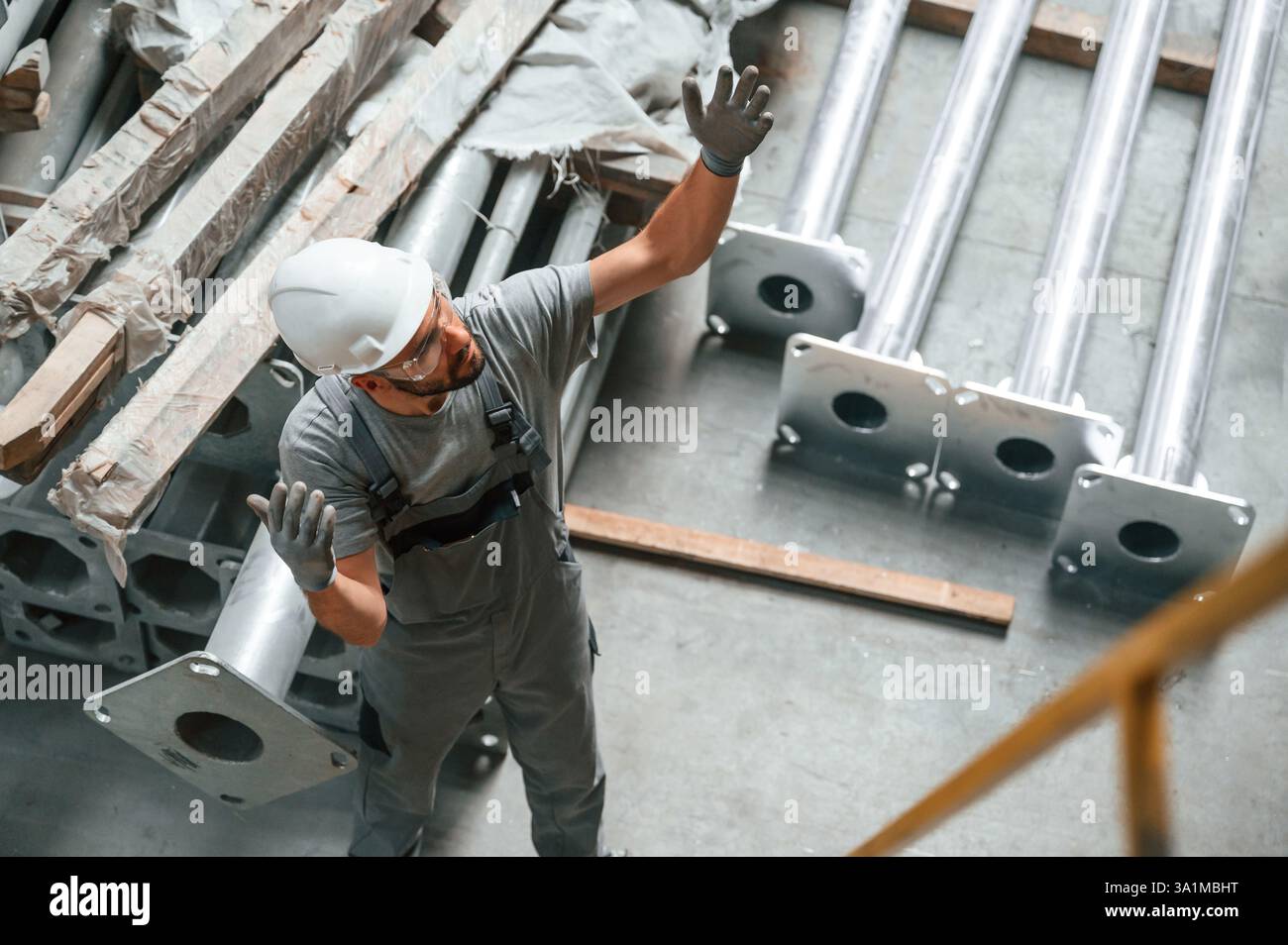Making gesture by hands. Young factory worker in grey uniform Stock ...