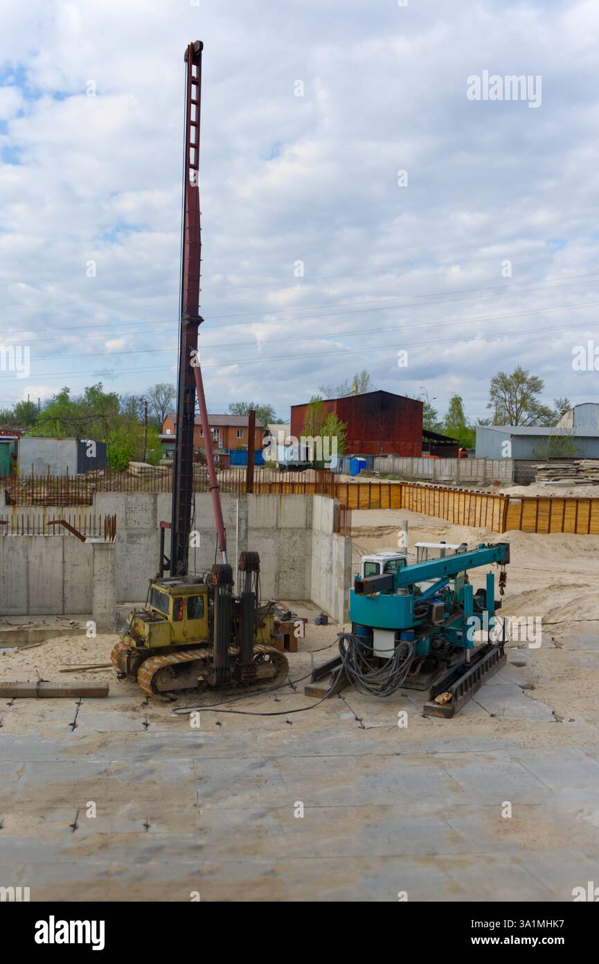 The image depicts a construction site with a pile driver and auxiliary ...